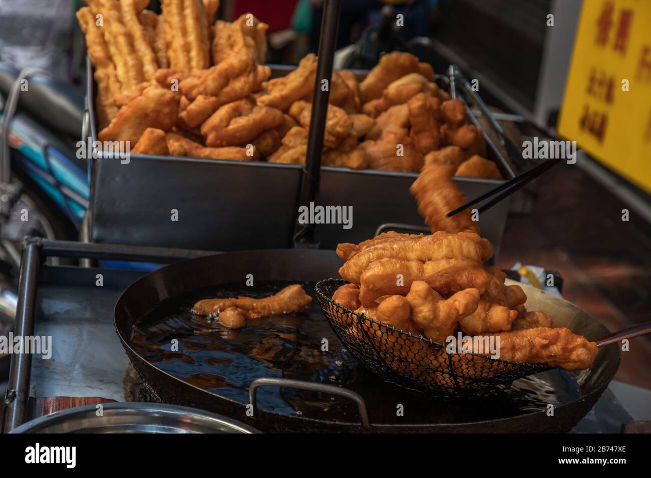 Chinese deep fried dough in hot oil on steel pan. Youtiao, Padnoongo or ...