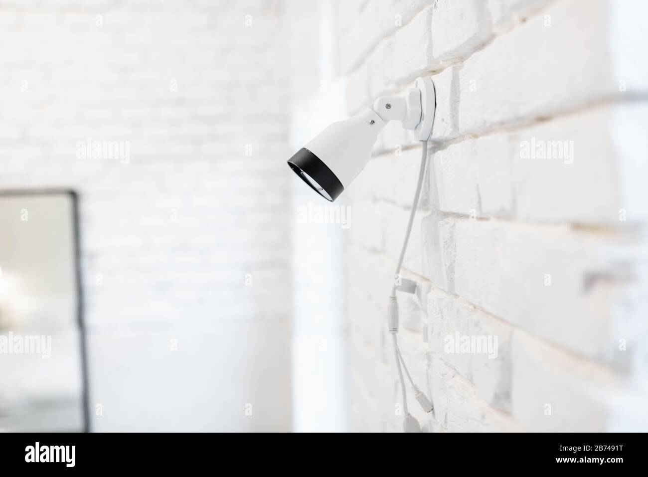 Surveillance ip camera mounted on the white brick wall indoors. Home ...