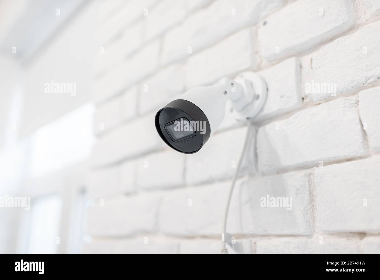 Surveillance ip camera mounted on the white brick wall indoors. Home ...