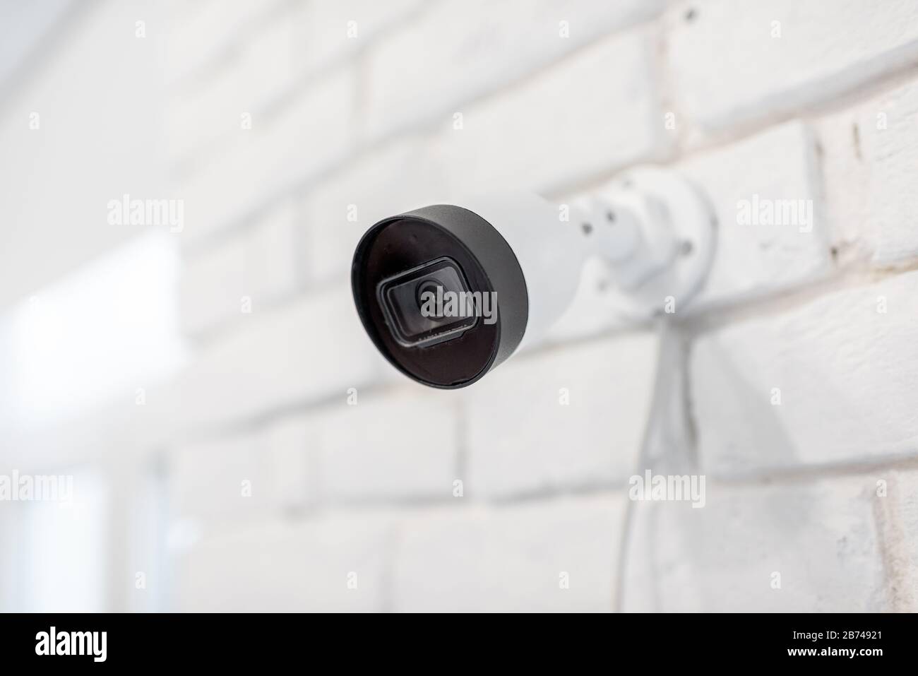 Surveillance ip camera mounted on the white brick wall indoors. Home ...