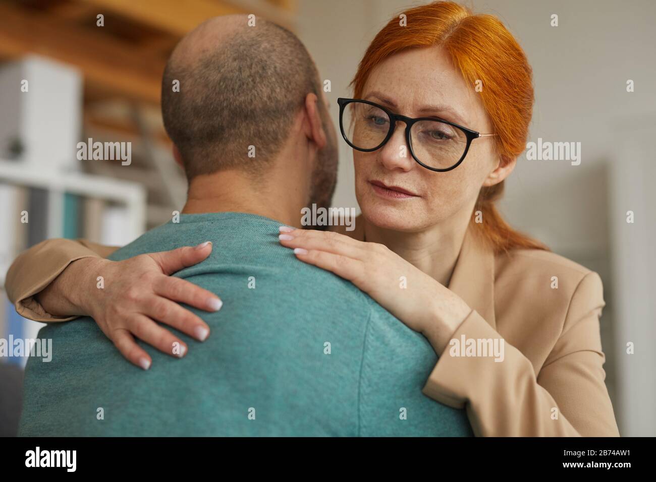 Red haired young woman sympathizing with a man she embracing and ...