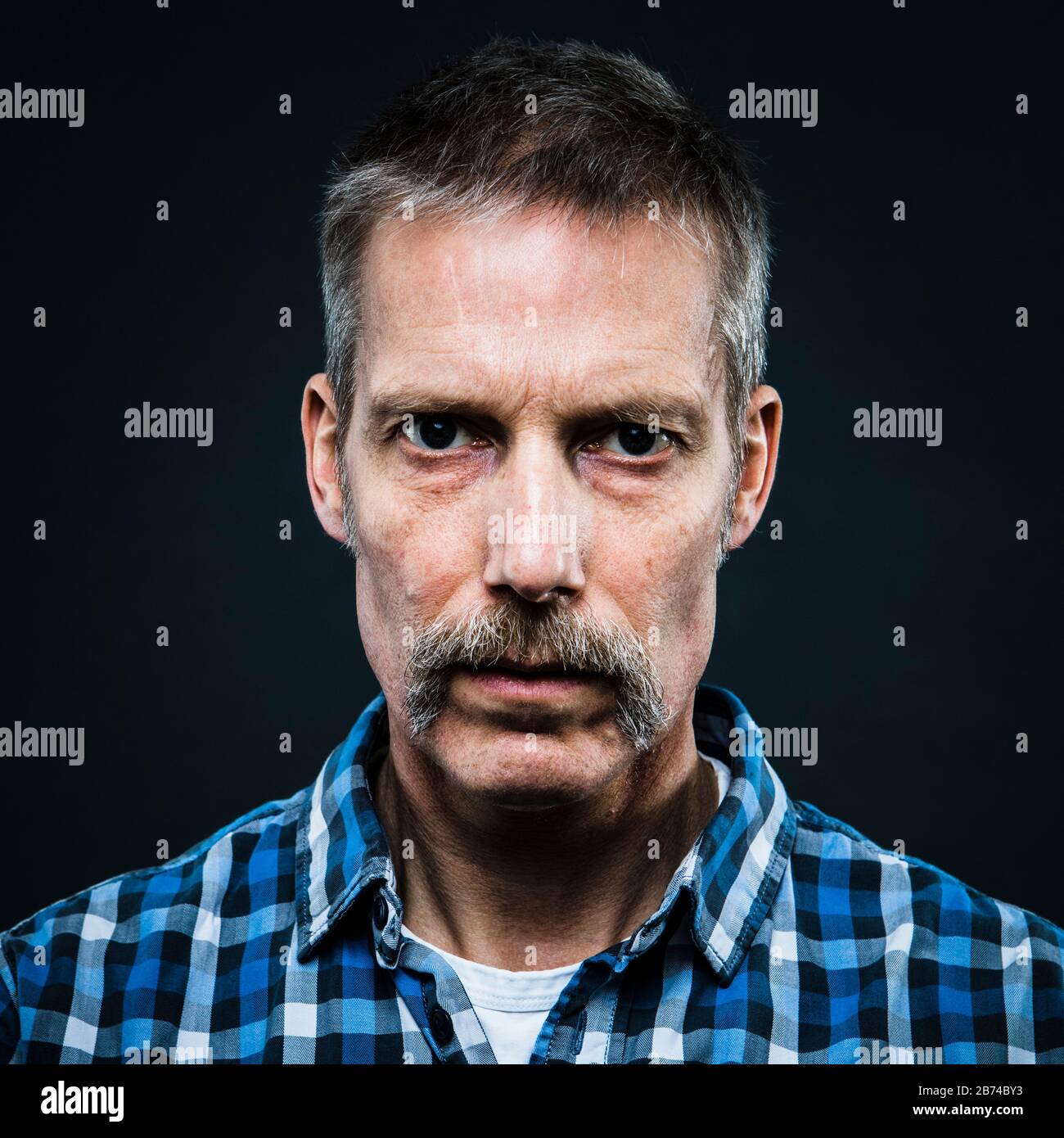 Man in his mid-50s with short hair and moustache and intense expression ...