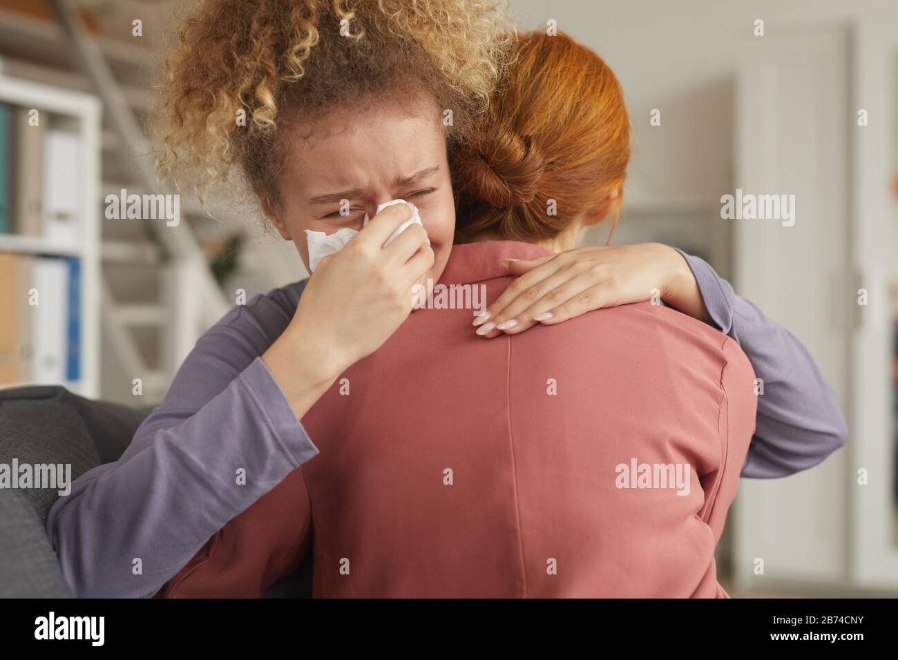 Young woman crying she has problems and her friend embracing her and ...
