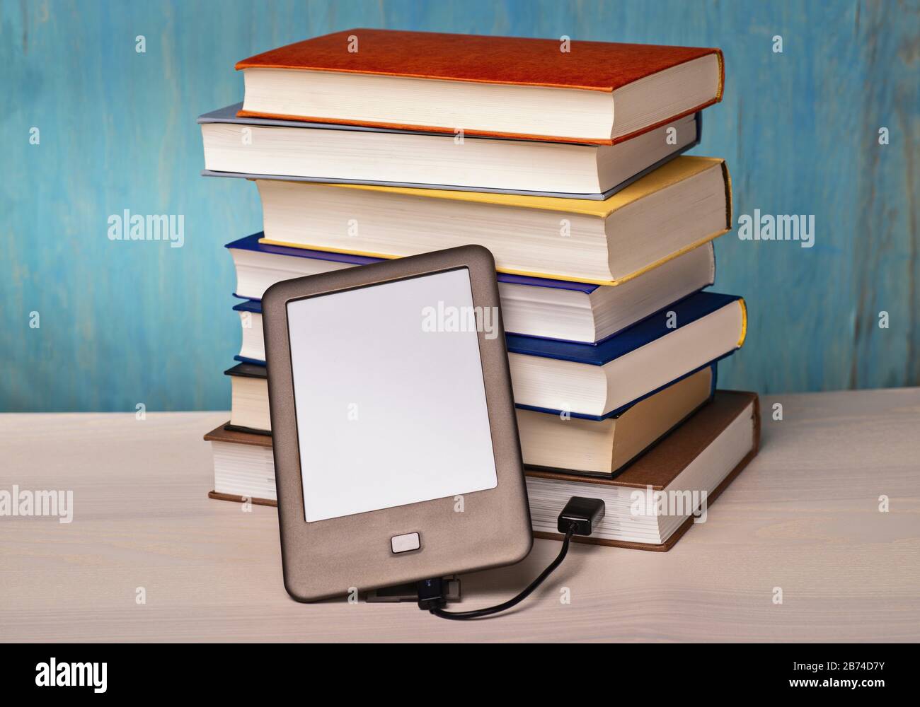 An e-book reader is connected to a stack of books via USB cable | usage ...