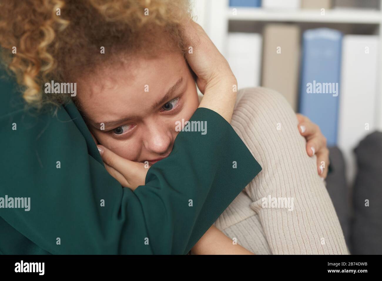 Close-up of sad woman crying while her friend embracing her and ...