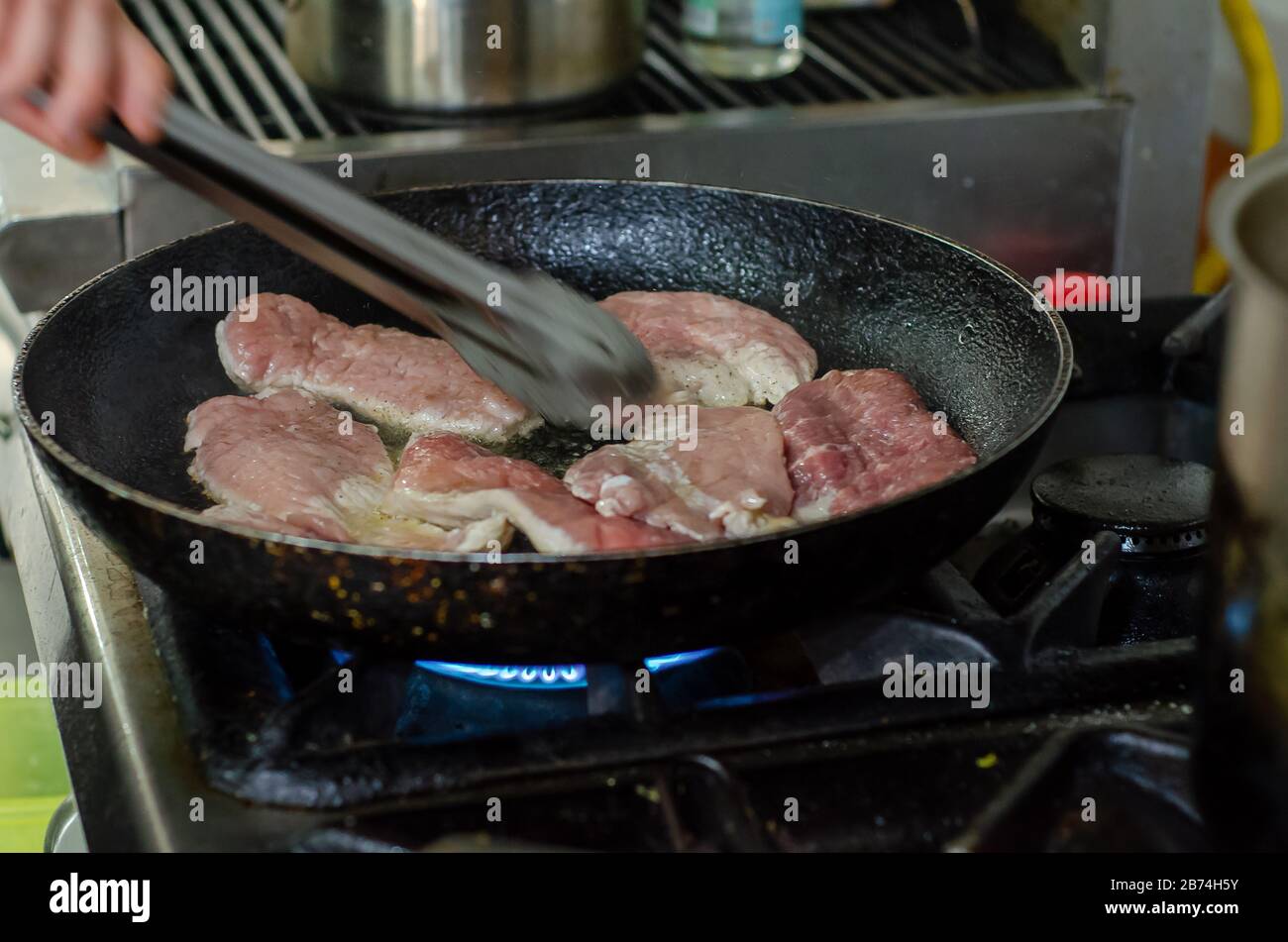 kitchen tweezers on move turn over cooking meat in frying pan Stock ...