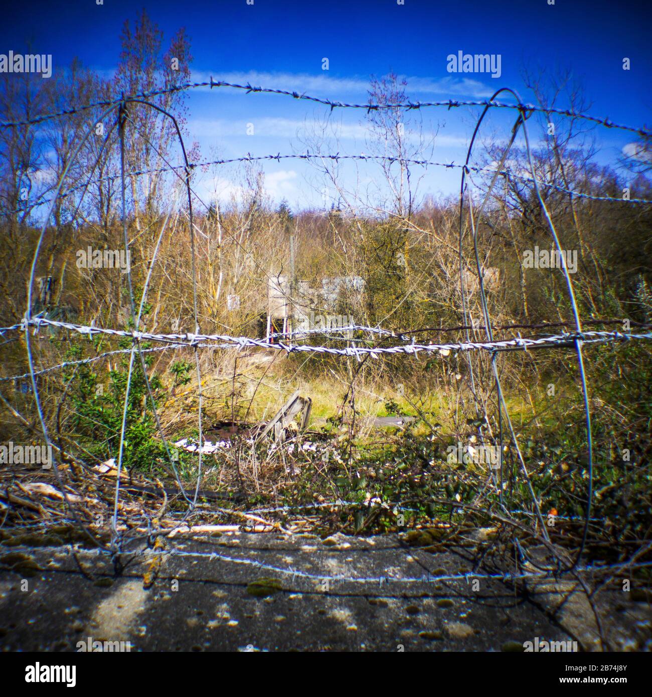 Concrete blocks and barbed wire enclose an abandonned place, digitally ...