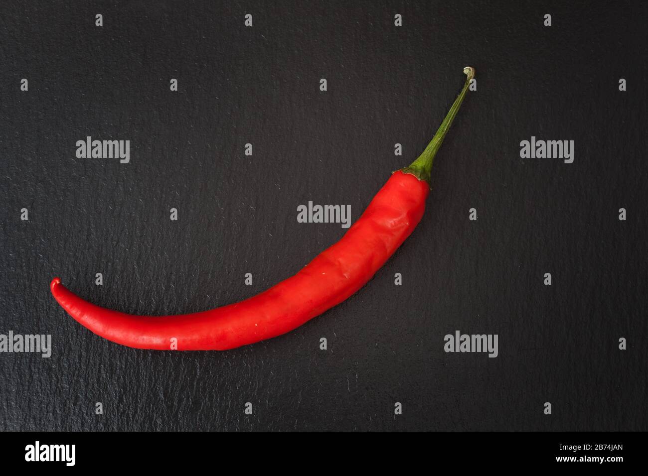 A red chilli pepper against a black background Stock Photo - Alamy