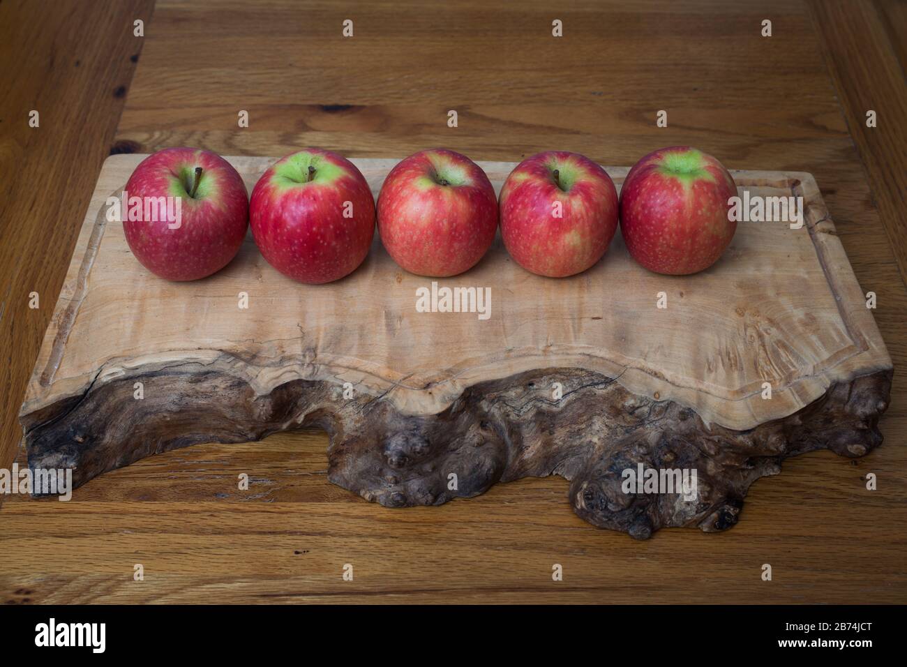 5 red apples on a natural wooden chopping board Stock Photo - Alamy