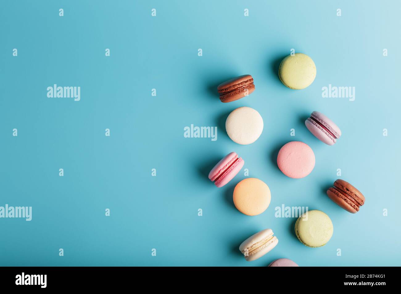 Macaroni cookies of different colors are scattered on a blue background ...