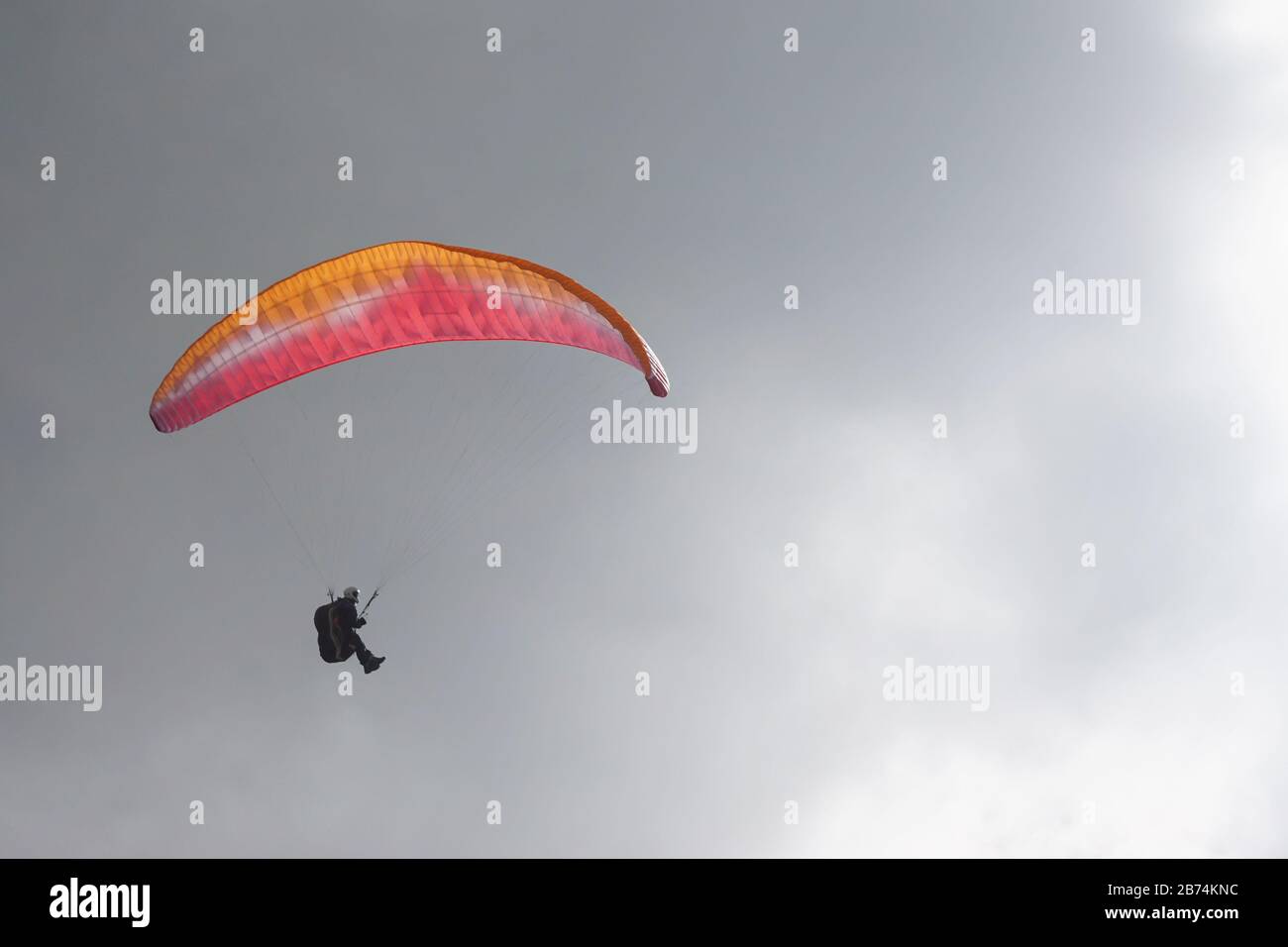 Paraglider in the sky against gray cloudy background Stock Photo - Alamy