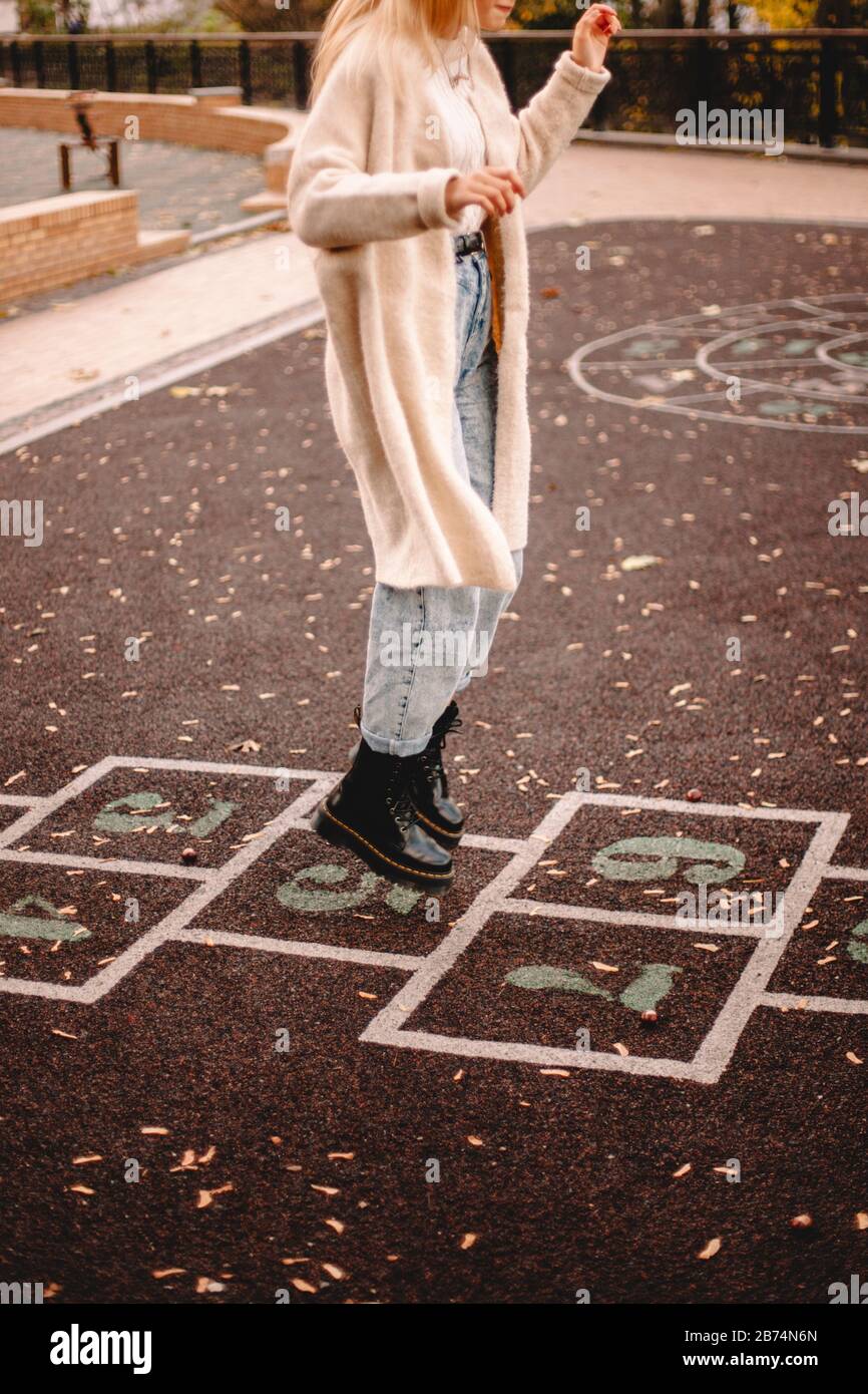 Teenage girl playing hopscotch in park during autumn Stock Photo - Alamy