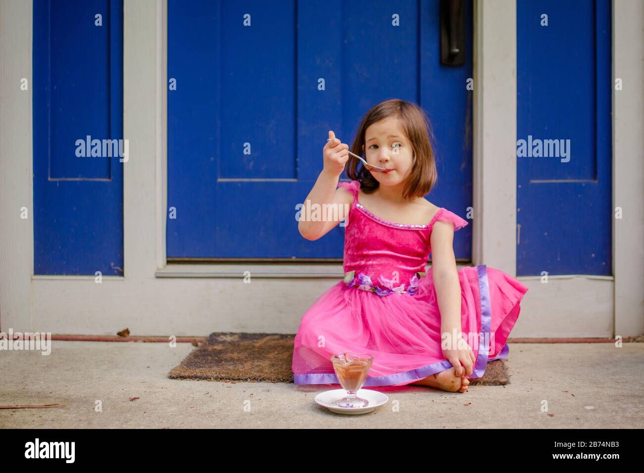 A little girl sits on her front stoop eating chocolate ice cream Stock ...
