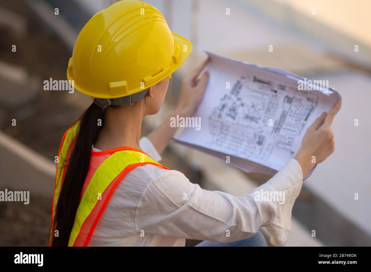 Woman Engineering design hard hat safety suit holding blueprint ...