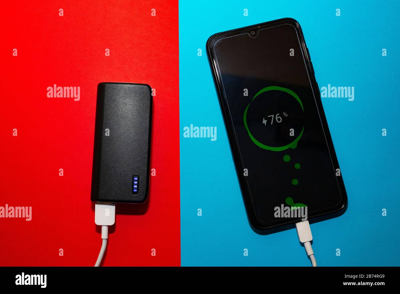 Powerbank loading a cell phone on a blue and red background. Powerbank ...