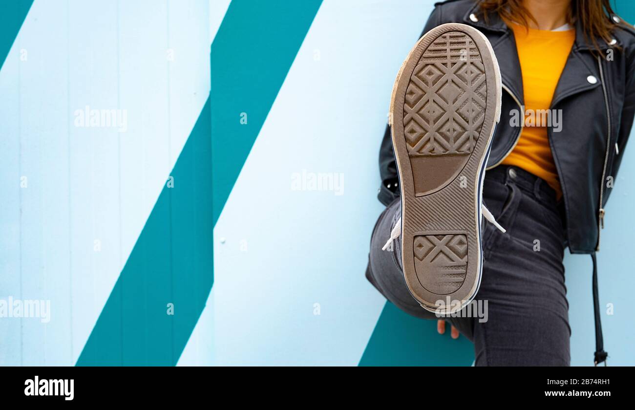 Woman showing the sole of her sneaker on a blue background. Kick ...