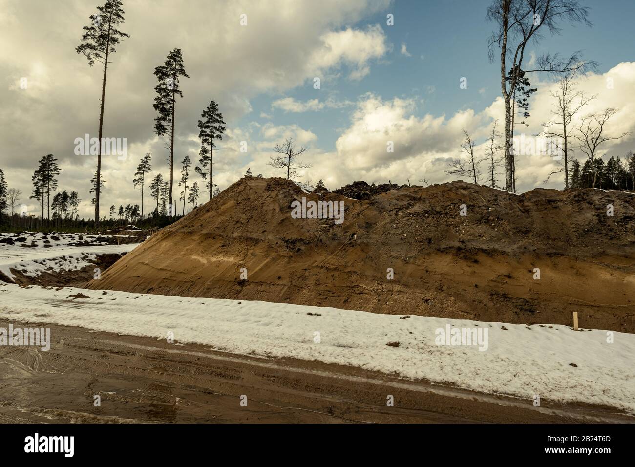 construction site of new road in forest in winter with snow and mud ...