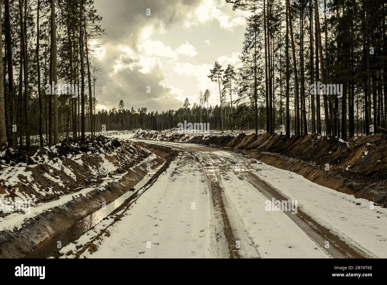 construction site of new road in forest in winter with snow and mud ...