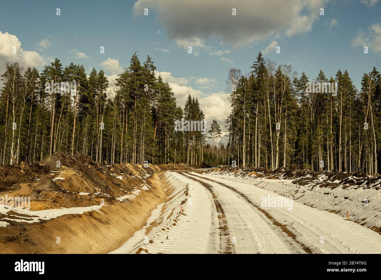 construction site of new road in forest in winter with snow and mud ...