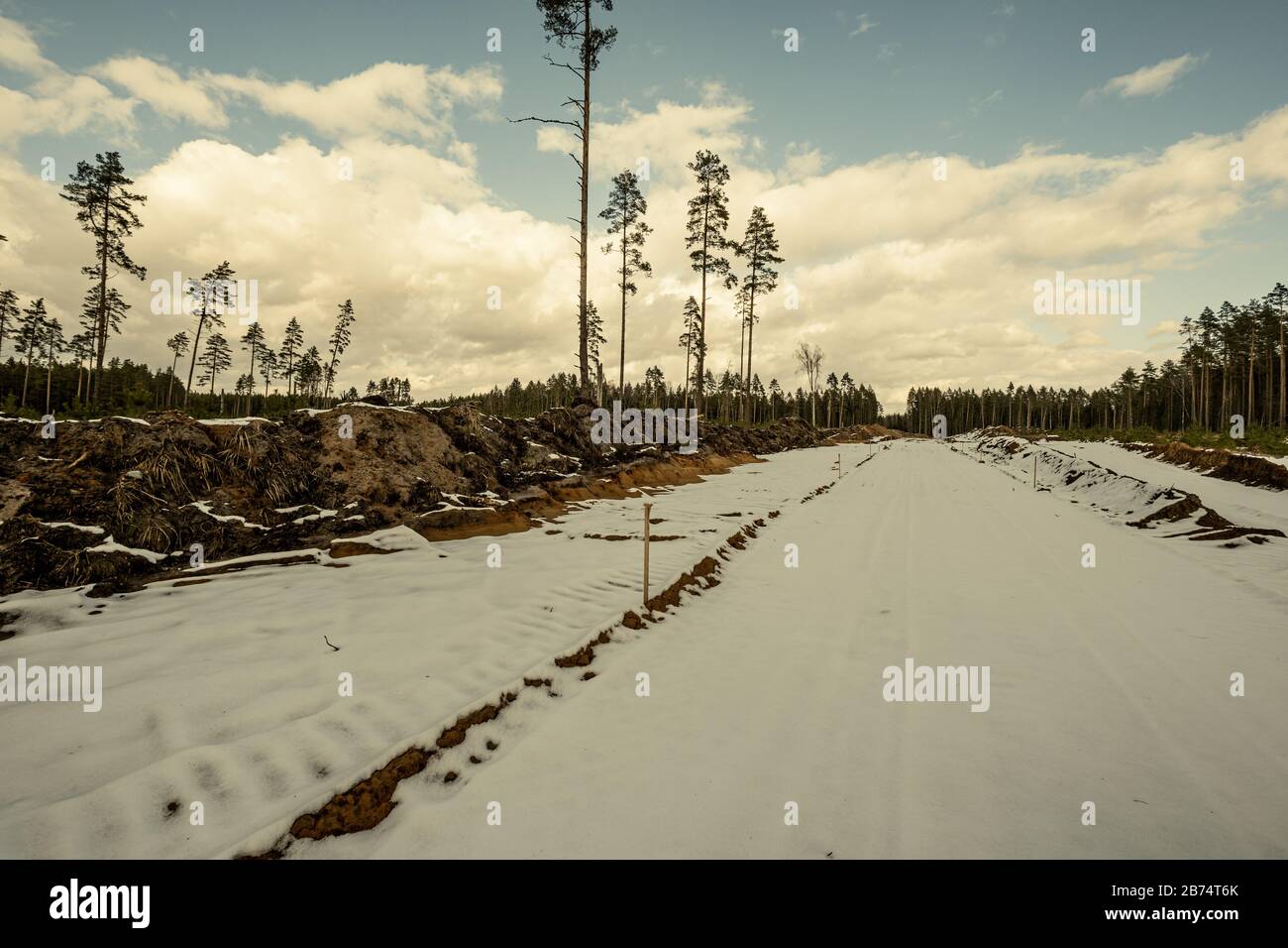 construction site of new road in forest in winter with snow and mud ...