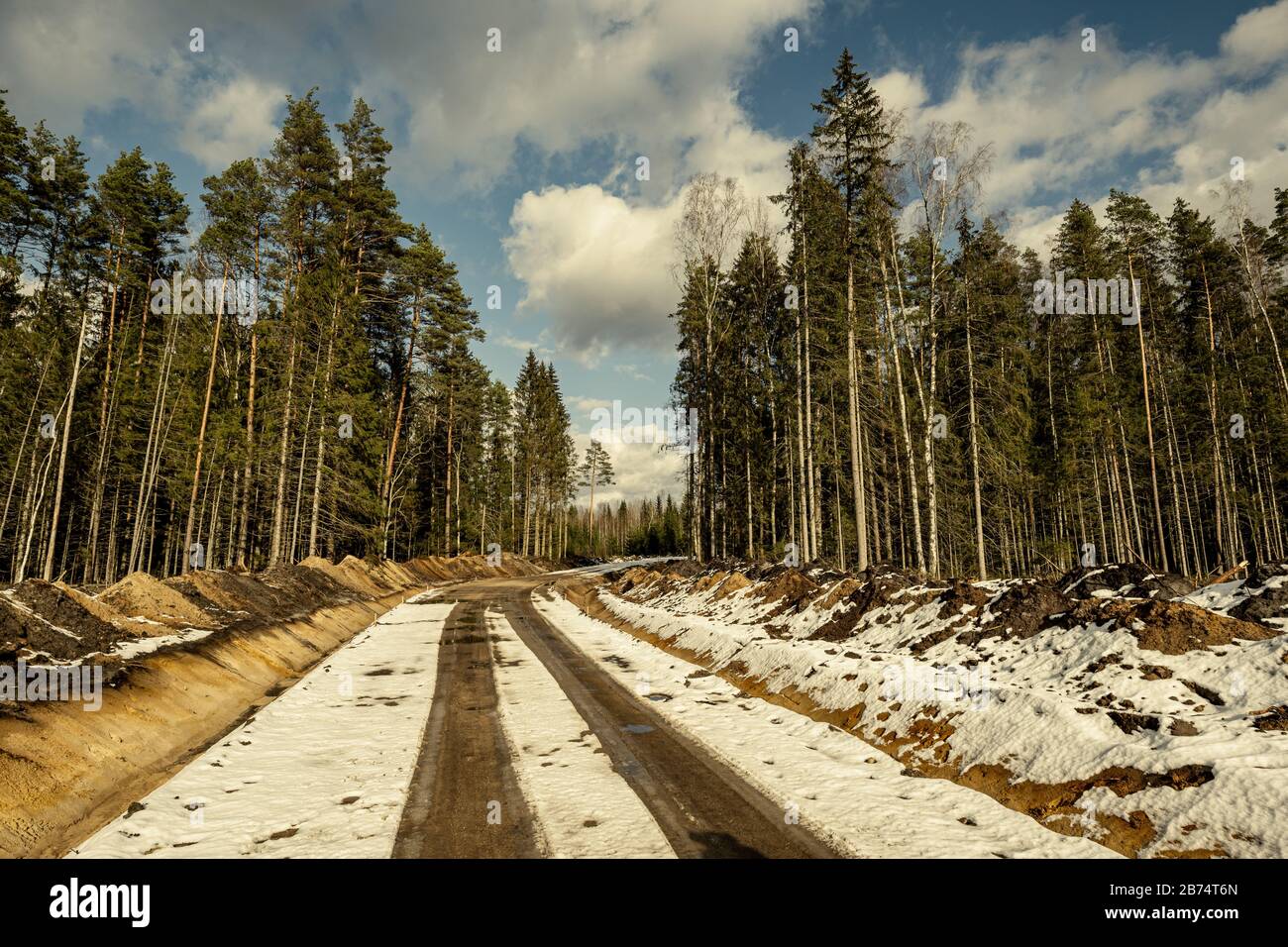 construction site of new road in forest in winter with snow and mud ...