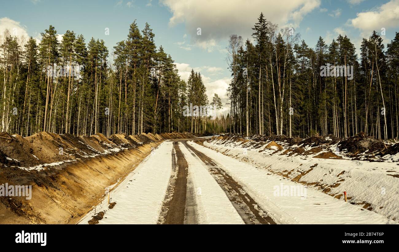 construction site of new road in forest in winter with snow and mud ...