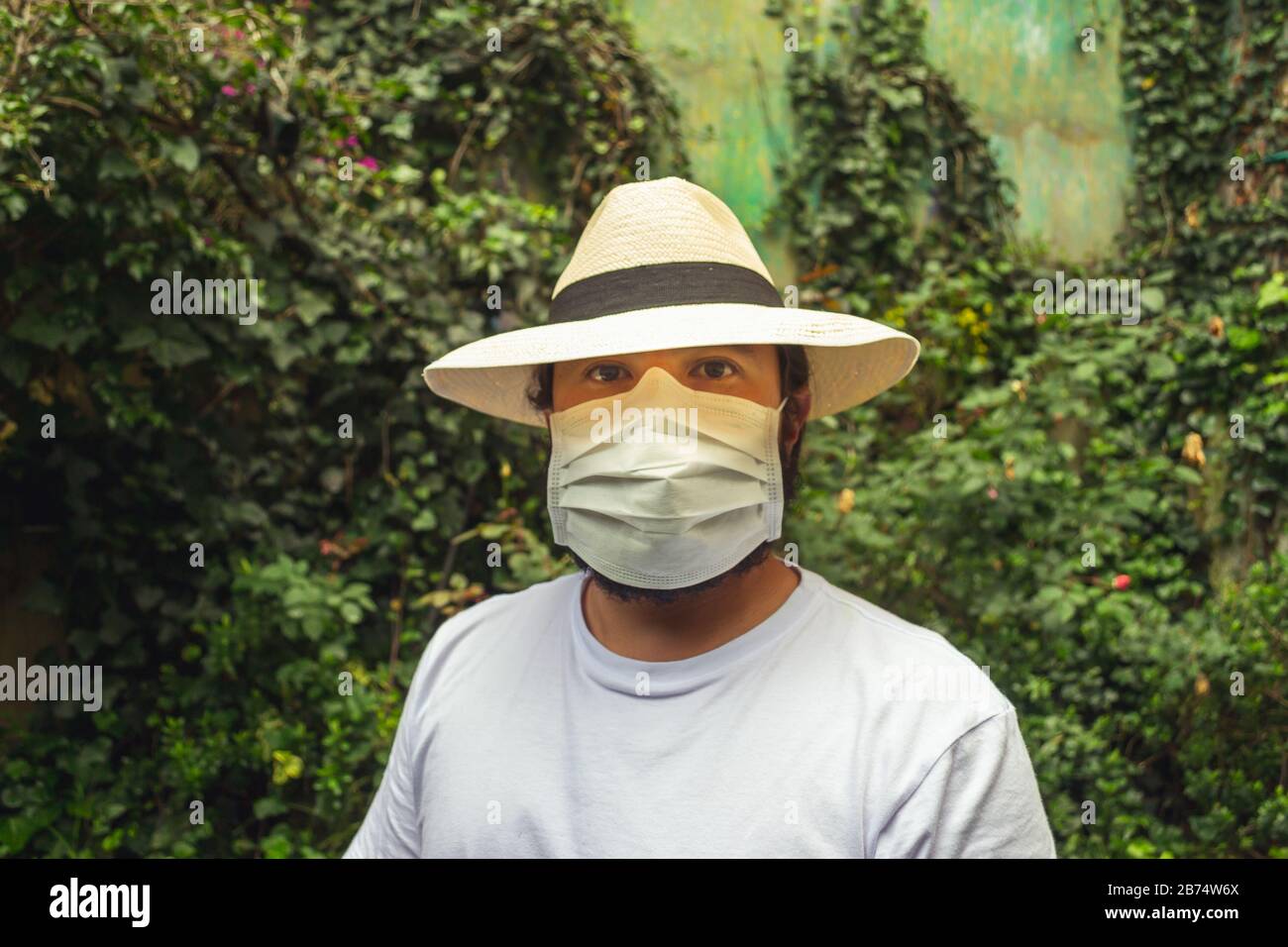 Man in a hat wearing a white face mask to protect from dust and ...