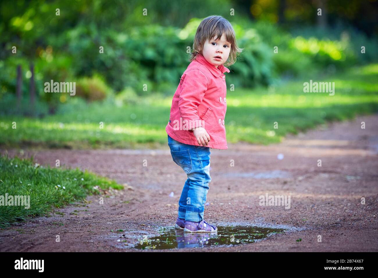 Little girl playing in a puddle Stock Photo - Alamy