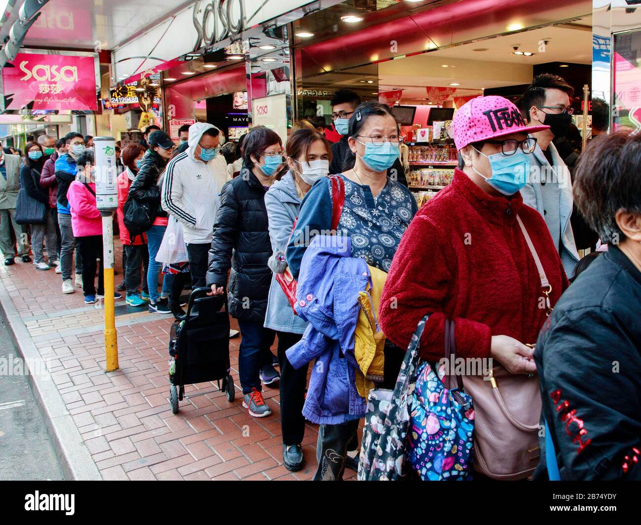 People line up to get free surgical masks from a pharmacy in Hong Kong ...