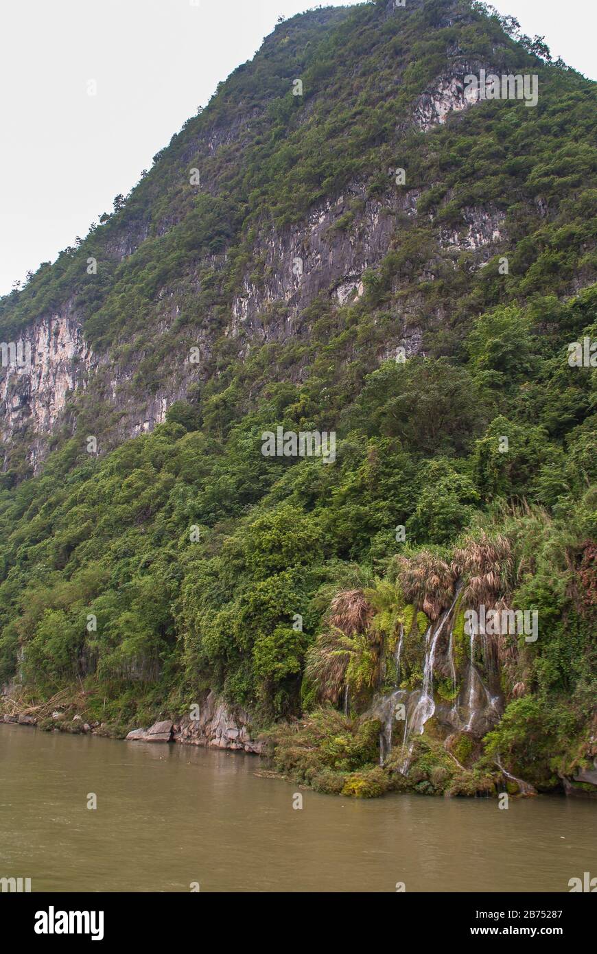 Guilin, China - May 10, 2010: Along Li River. Waterfall off karst ...