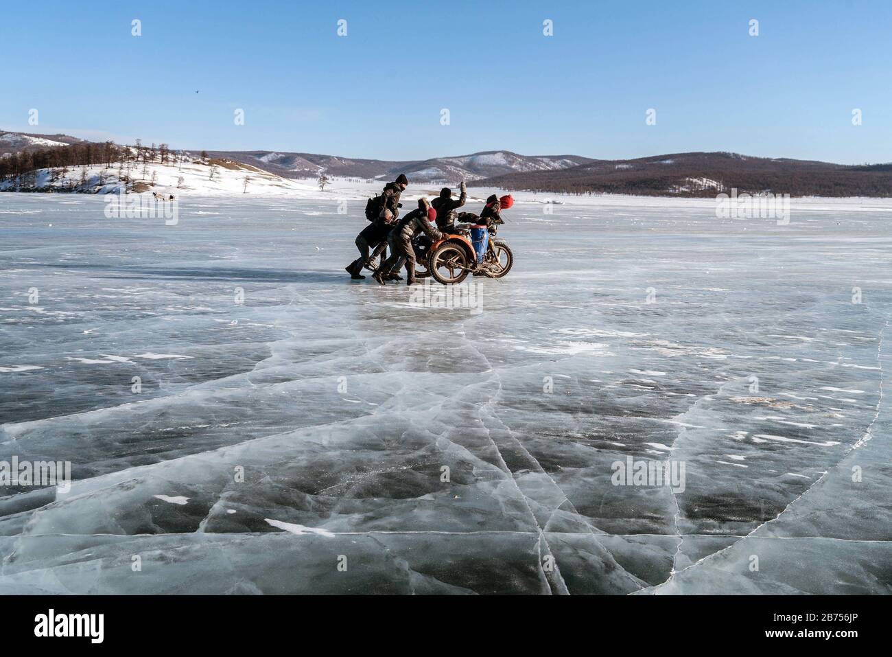 A couple of kids pushing a broken down motorcycle. [automated ...