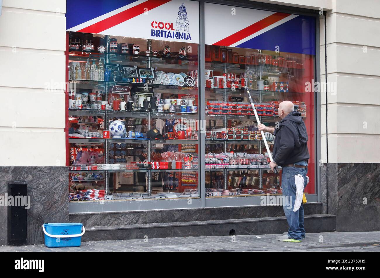 A window cleaner cleans the windows of a "Cool Britannia" souvenir shop ...