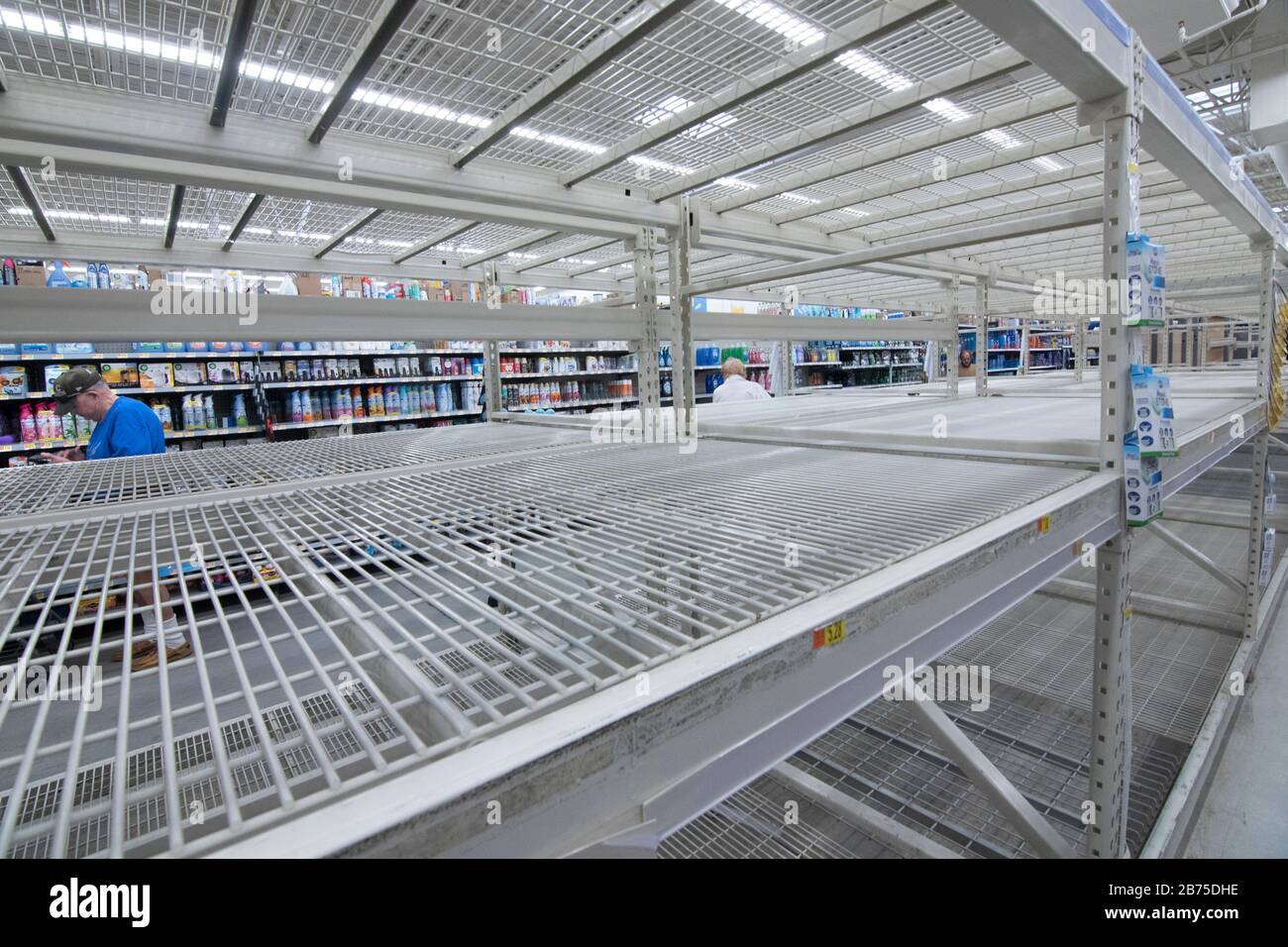 Unidentified shoppers pas by empty shelves in the Walmart store in ...
