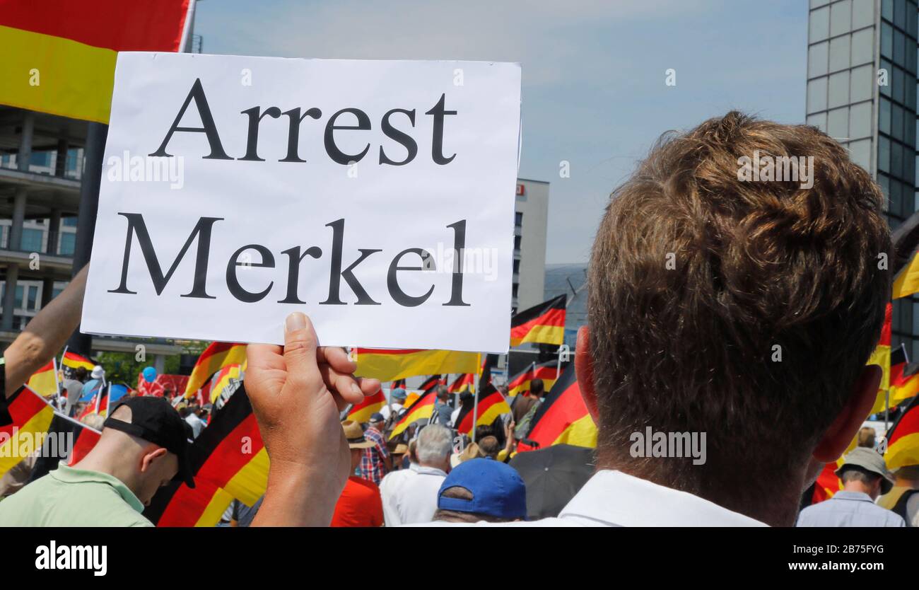 An AfD supporter holds a sign with the inscription "Arrest Merkel ...