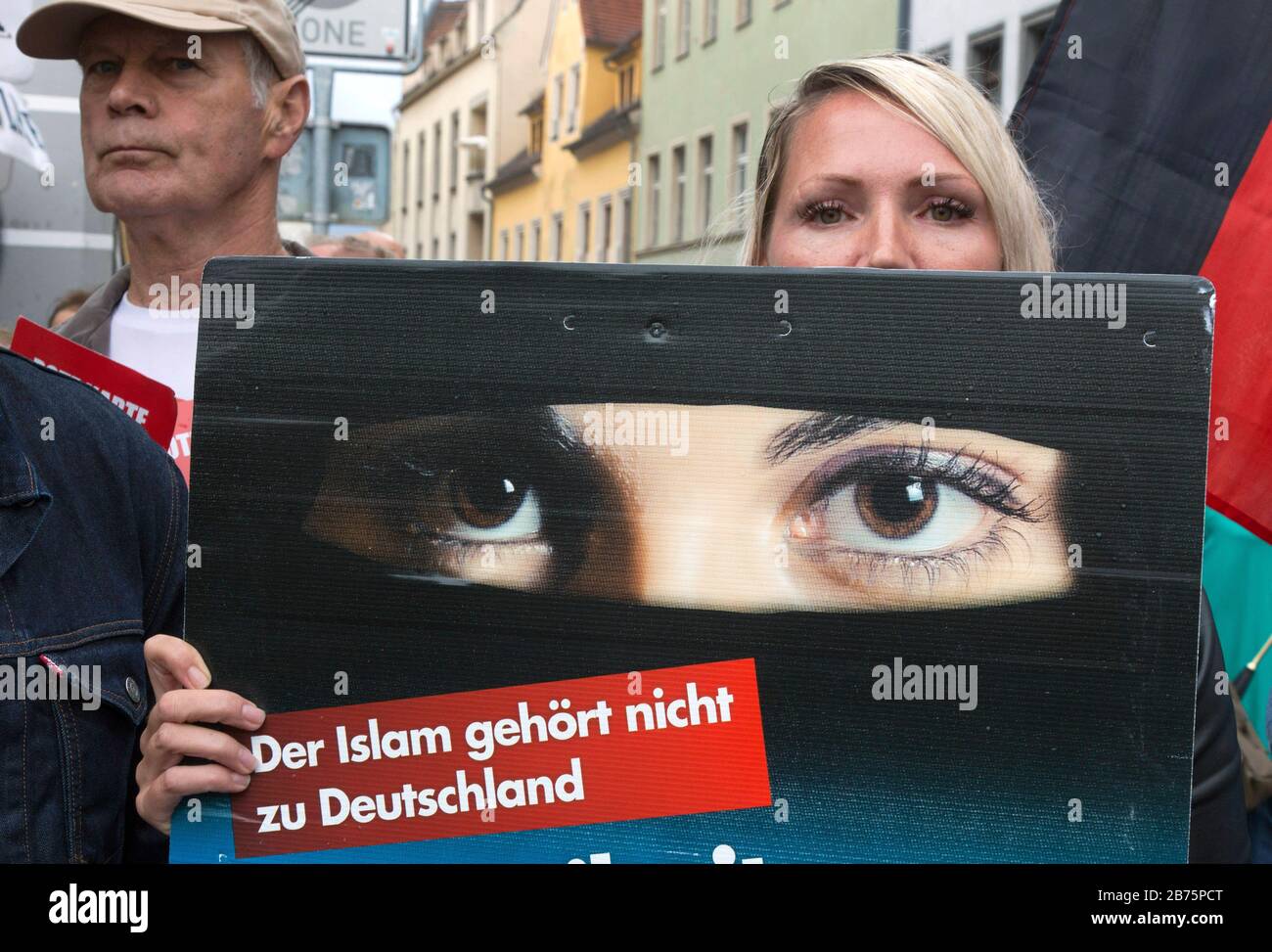 An AfD supporter shows a poster with the inscription "Islam does not ...