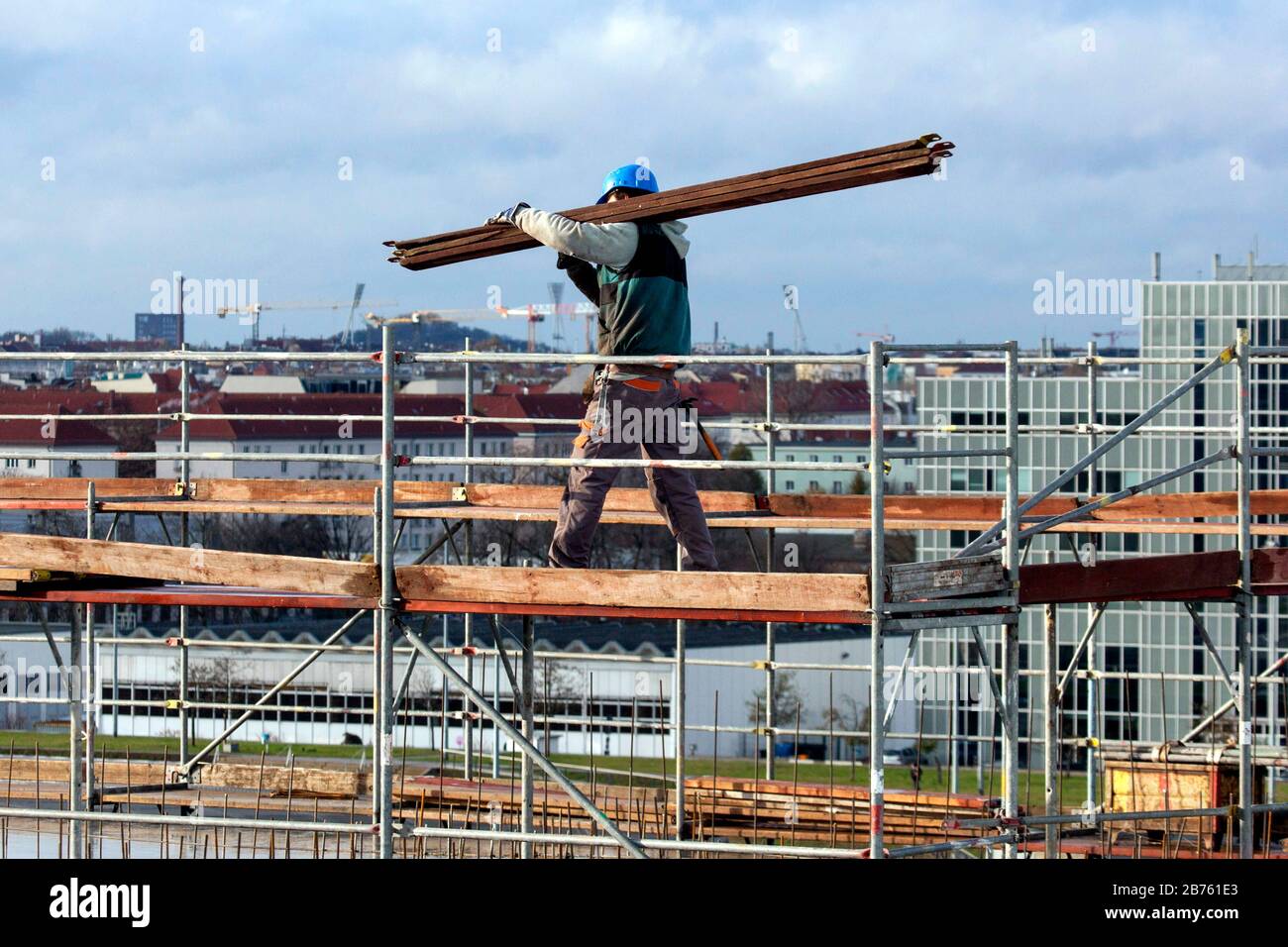 A construction worker transports wooden planks for scaffolding on a ...
