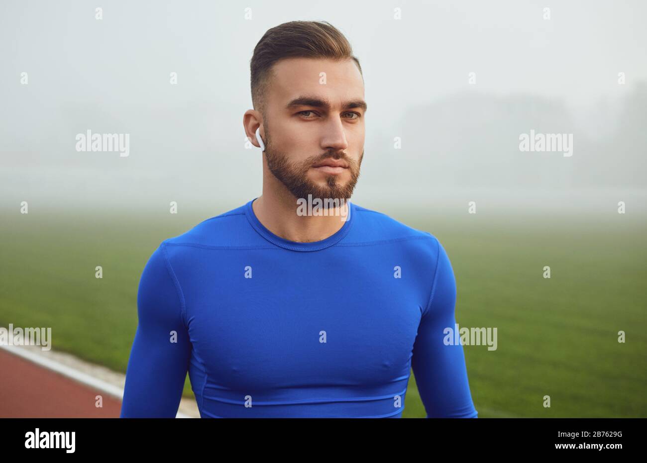 A sports guy in blue clothes smiles while looking at the stadium in the ...