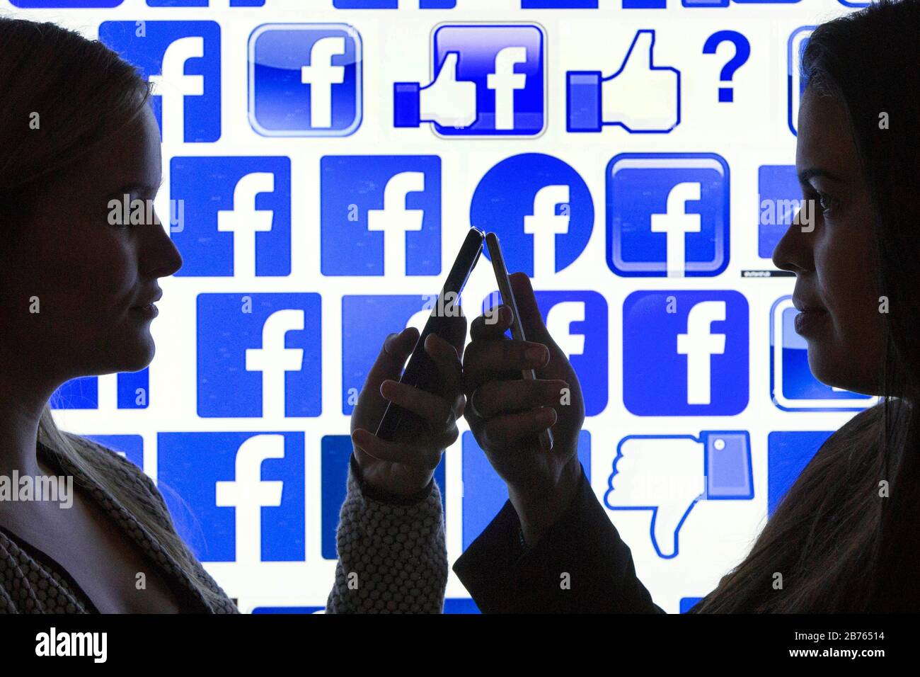 The silhouettes of two women with smartphones in their hands can be ...