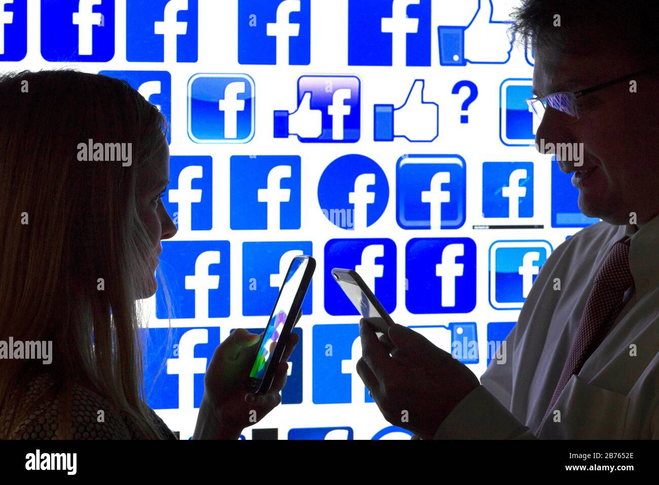 The silhouettes of a woman and a man with a smartphone in their hands ...
