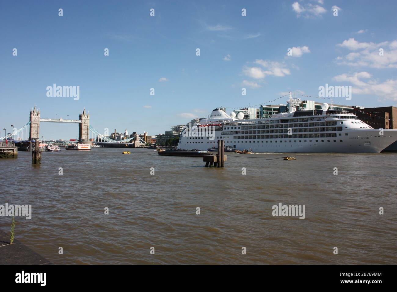 a white cruise ship docked in the river thames along the banks of ...