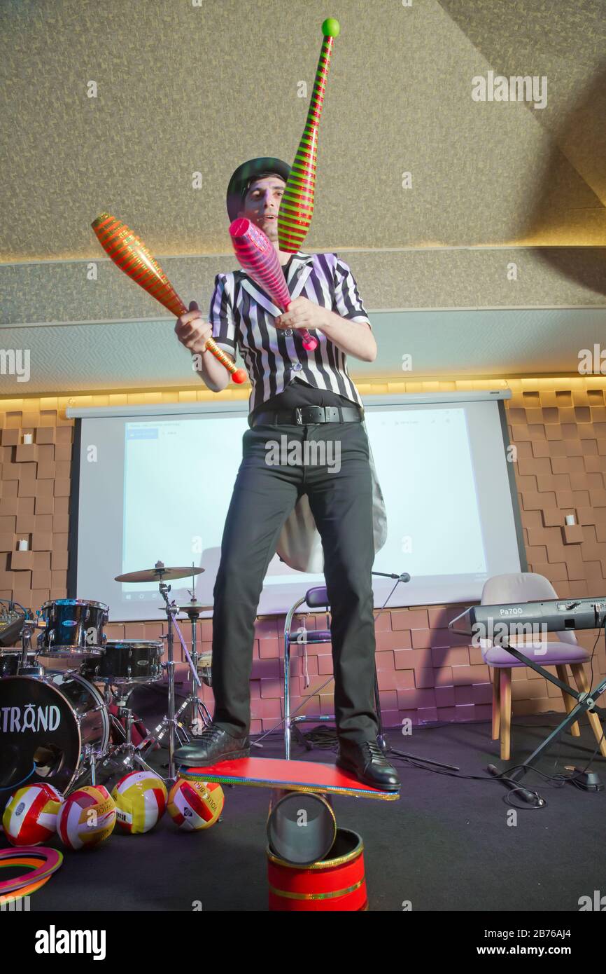Man standing on top of cylinders and juggling glass bottles, one bottle ...