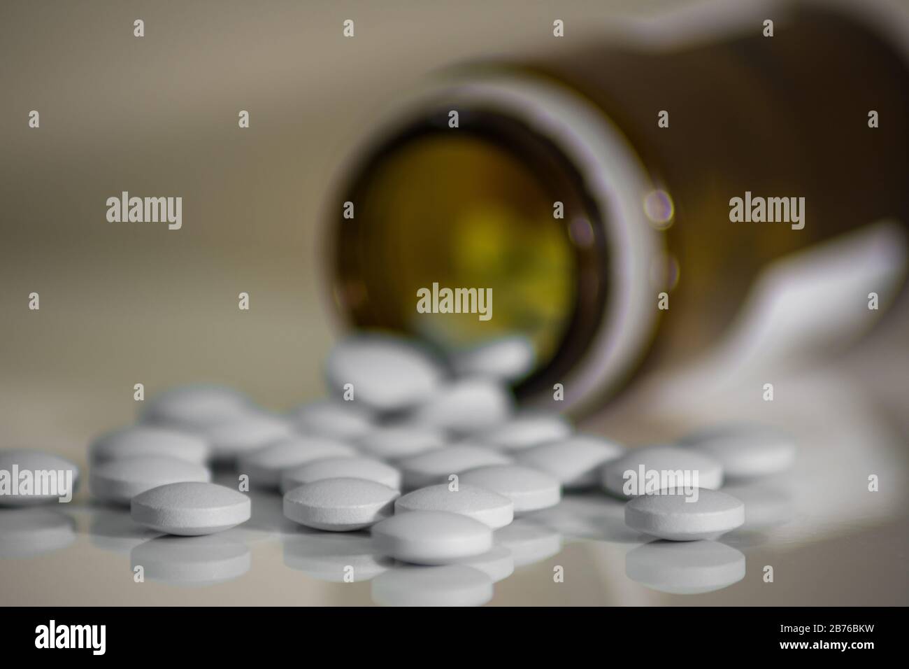 Spilled white medical pills from a brown glass, little tablets helping ...