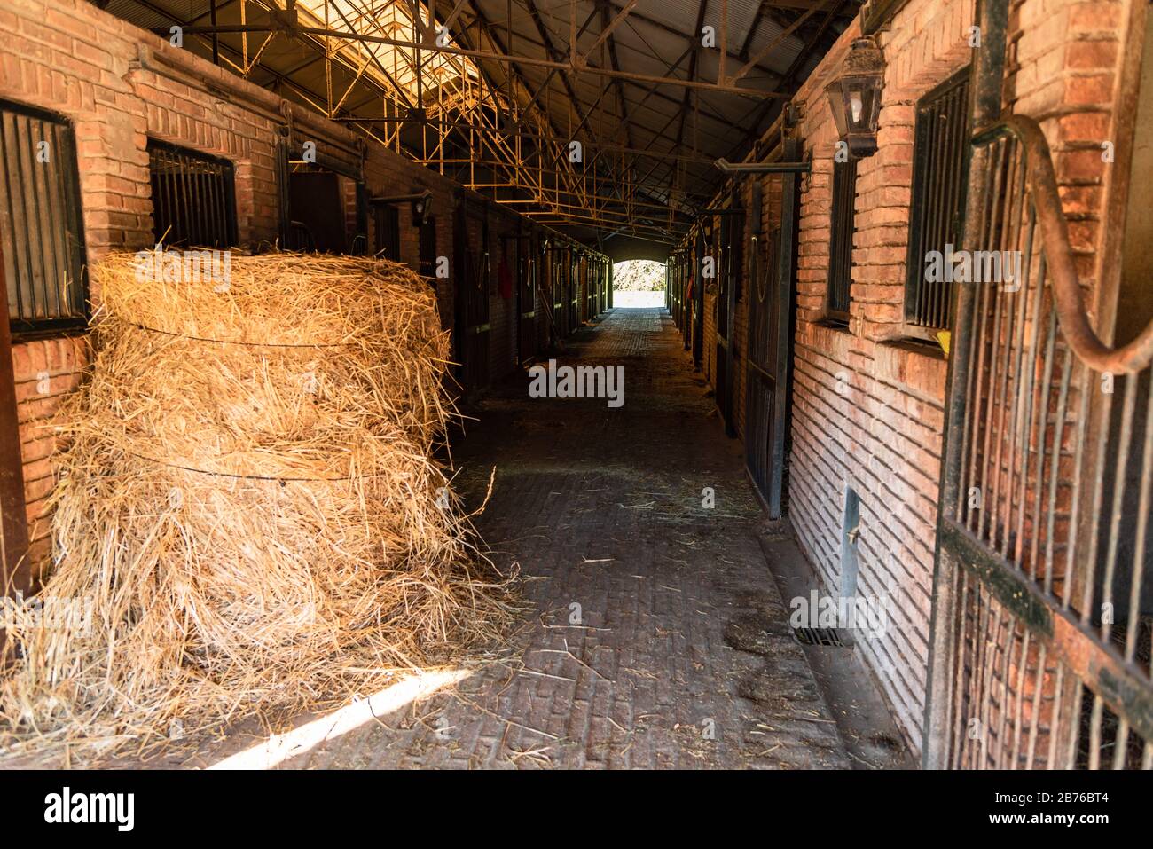 Inside a bricks stable with a lot of horses stals and a hay bale Stock ...