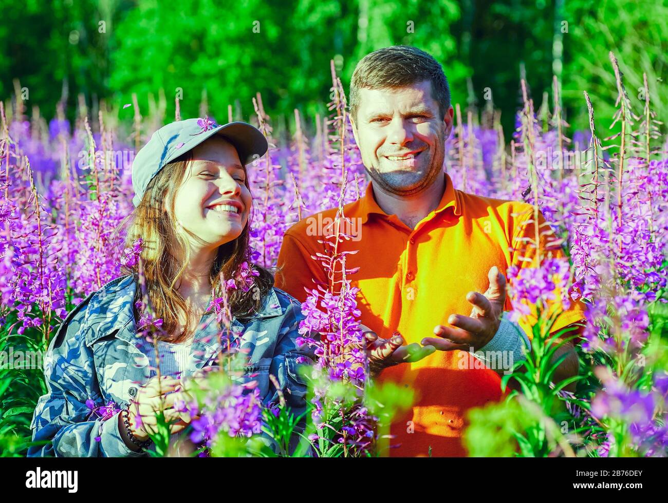 A young girl and a man are hugging each other in the tall grass with ...