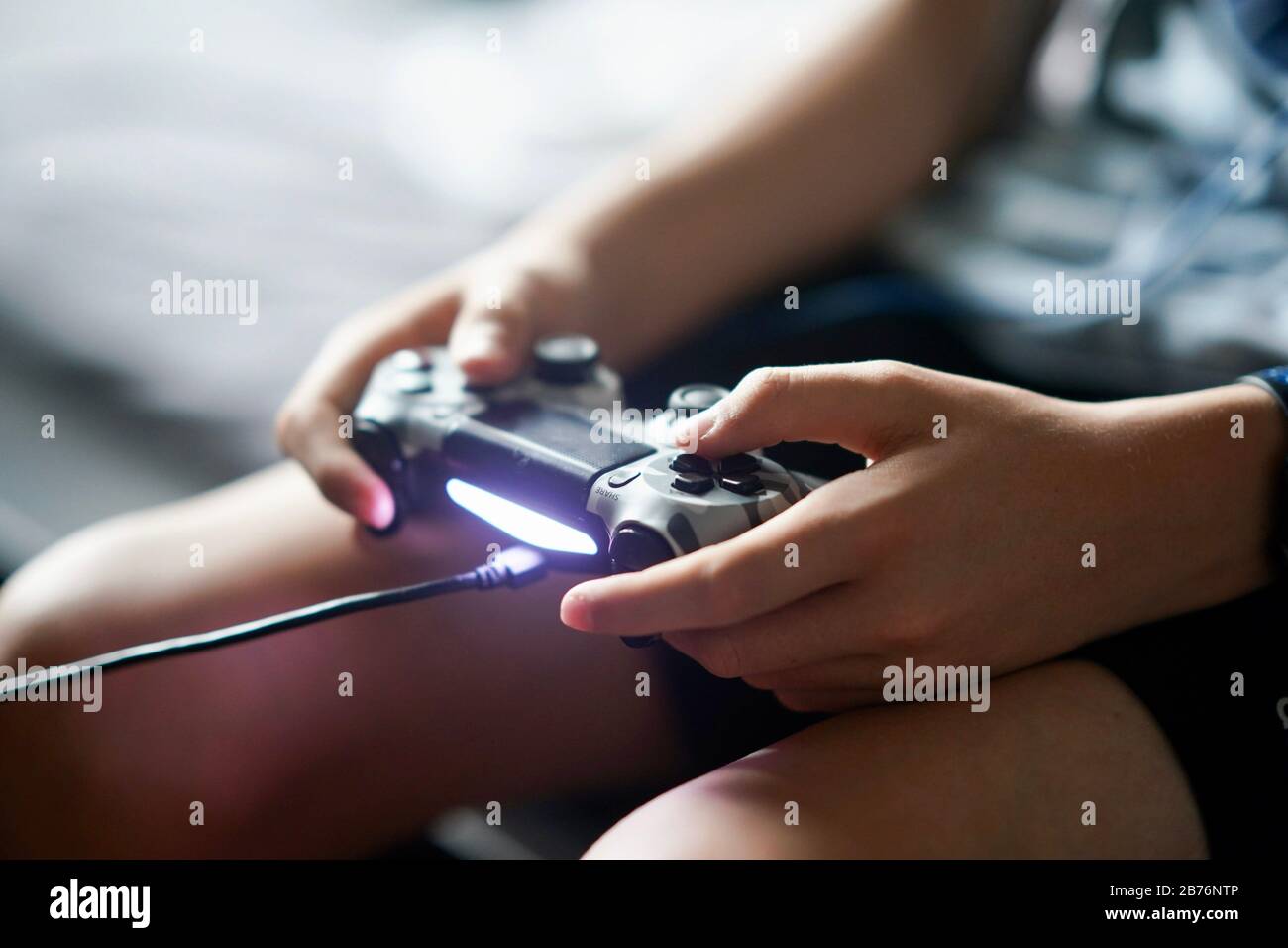 A close up of a video game controller while a teenage boy plays Stock ...