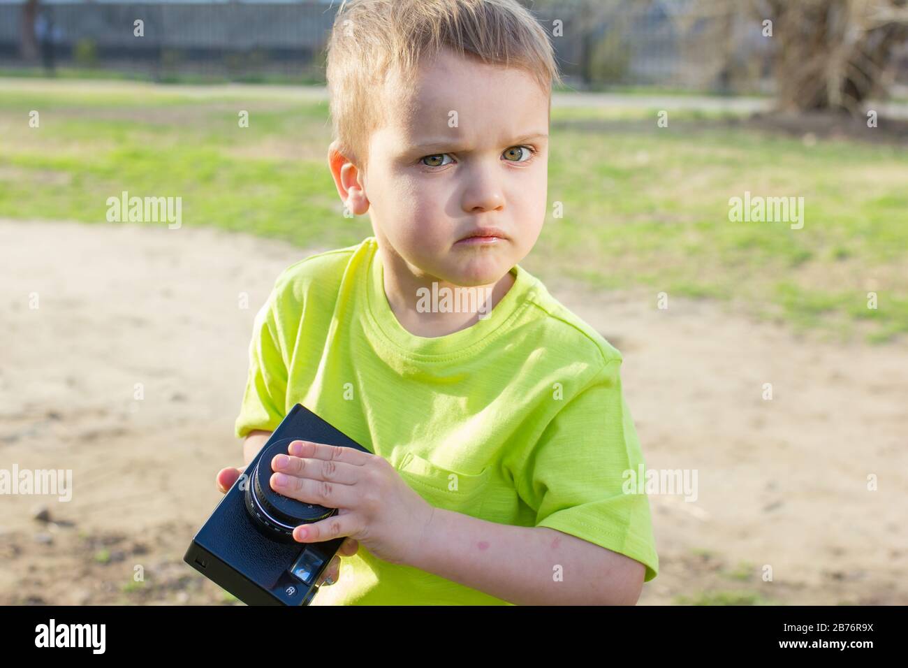 sly little boy in a green shirt with a camera in disbelief looks at the ...