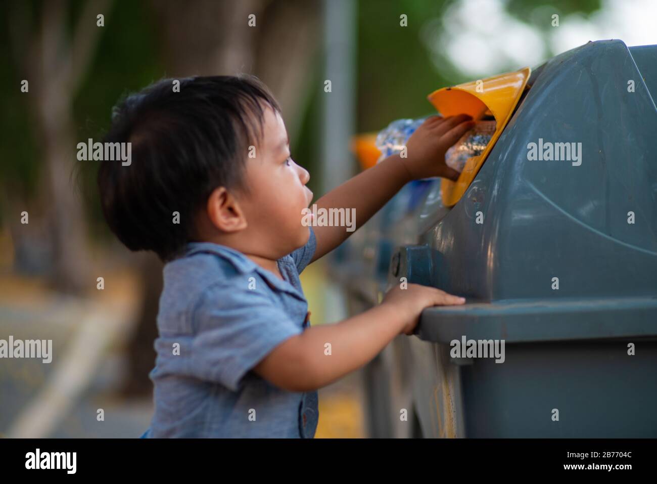 Little asian toddler baby boy throwing plastic bottle in recycling ...