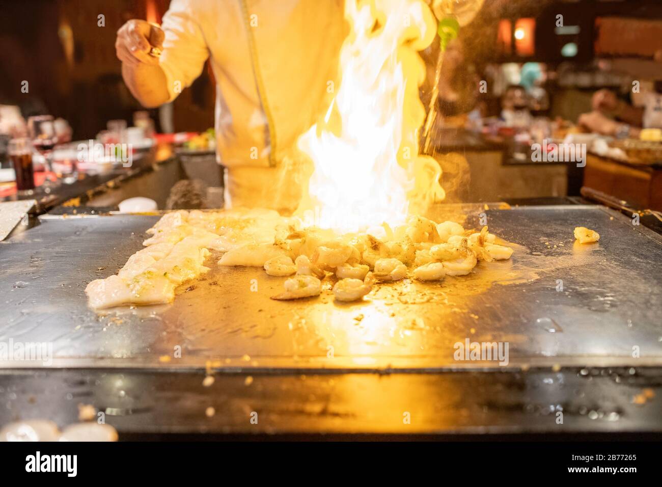 Teppanyaki chef cooking Japanese seafood and shrimp on hot metal plate ...