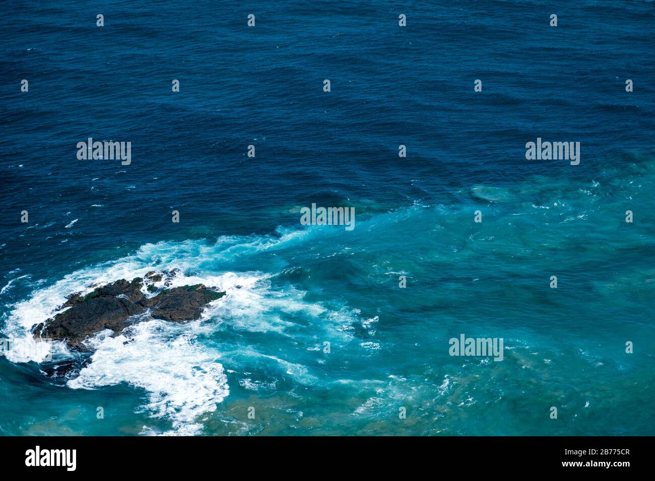 Aerial shot of a wavy sea with two streams crossing at a certain point ...