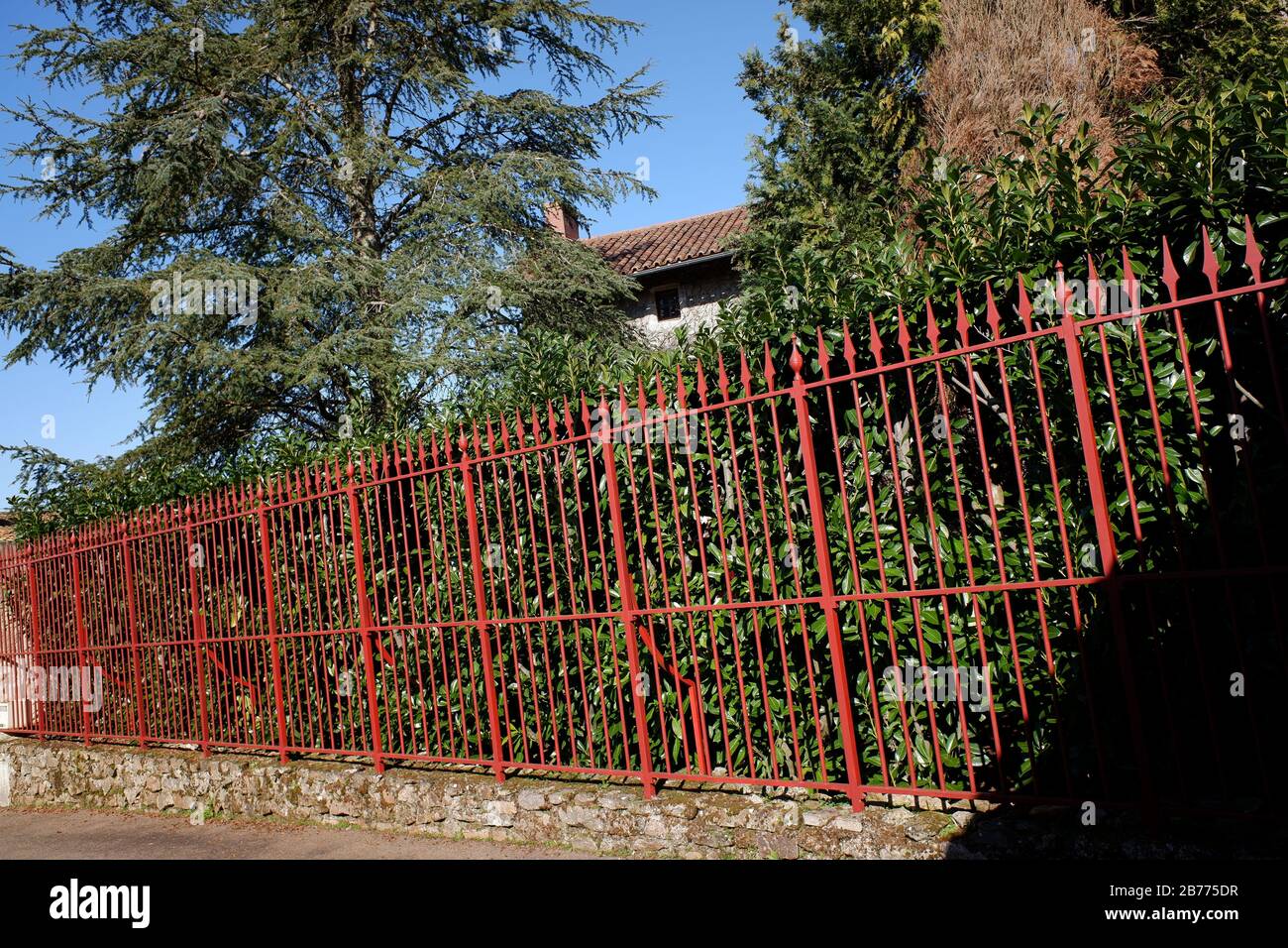 Shot of the red steel fence with bushes in the background Stock Photo ...
